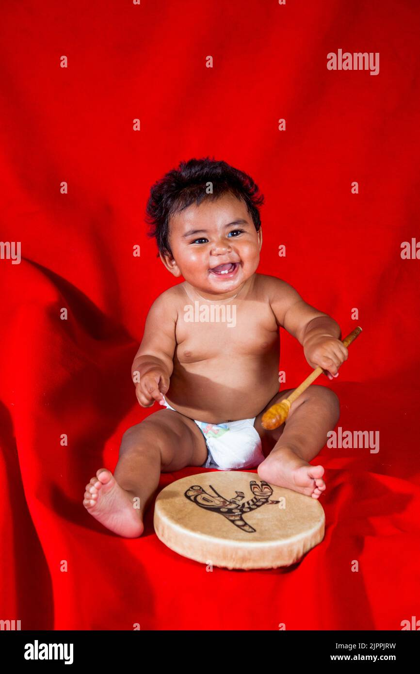 Happy Native American baby plays a traditional hand drum form the ...