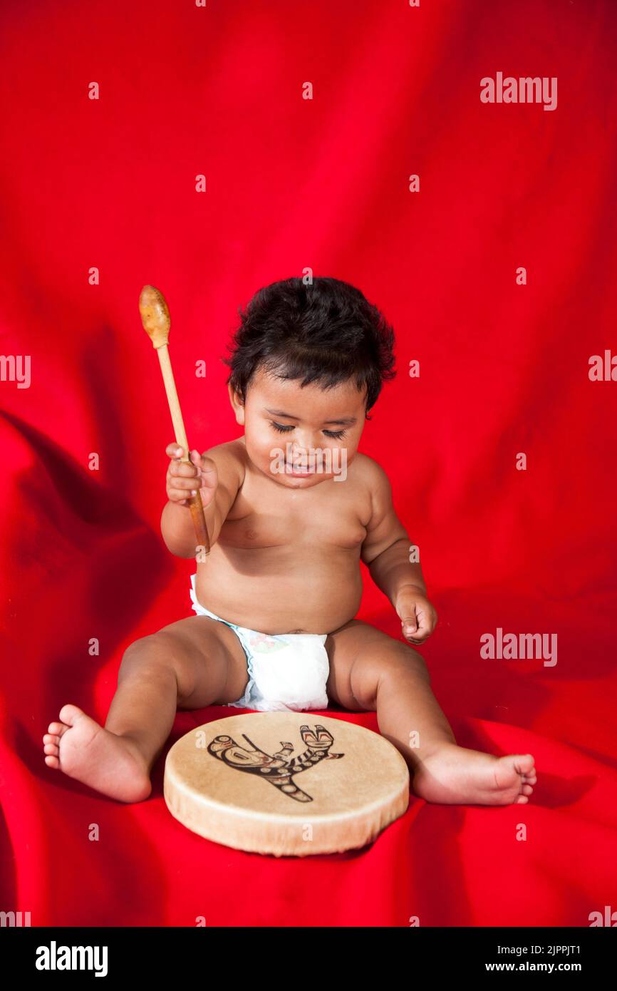 Happy Native American baby plays a traditional hand drum form the ...