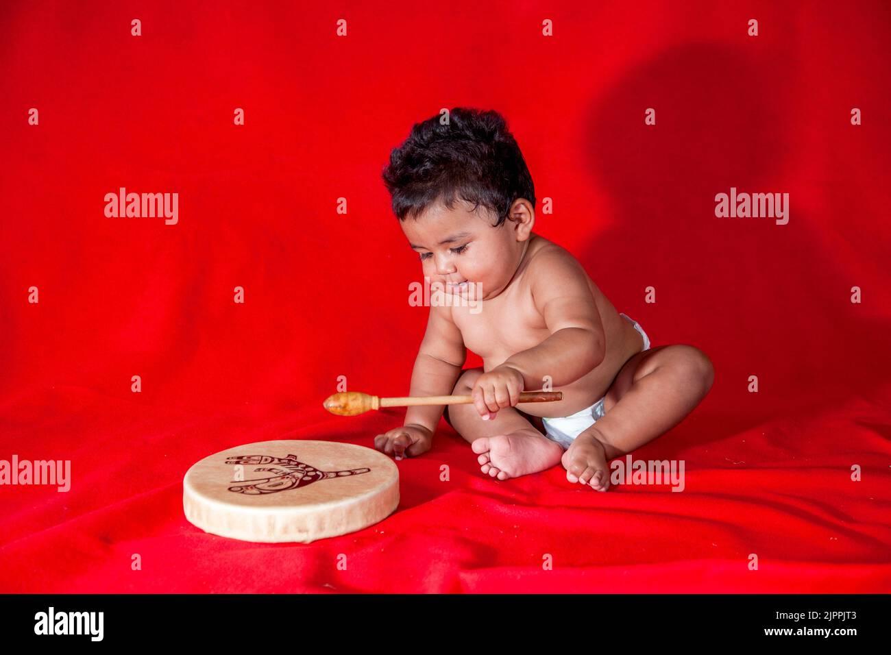 Happy Native American baby plays a traditional hand drum form the ...