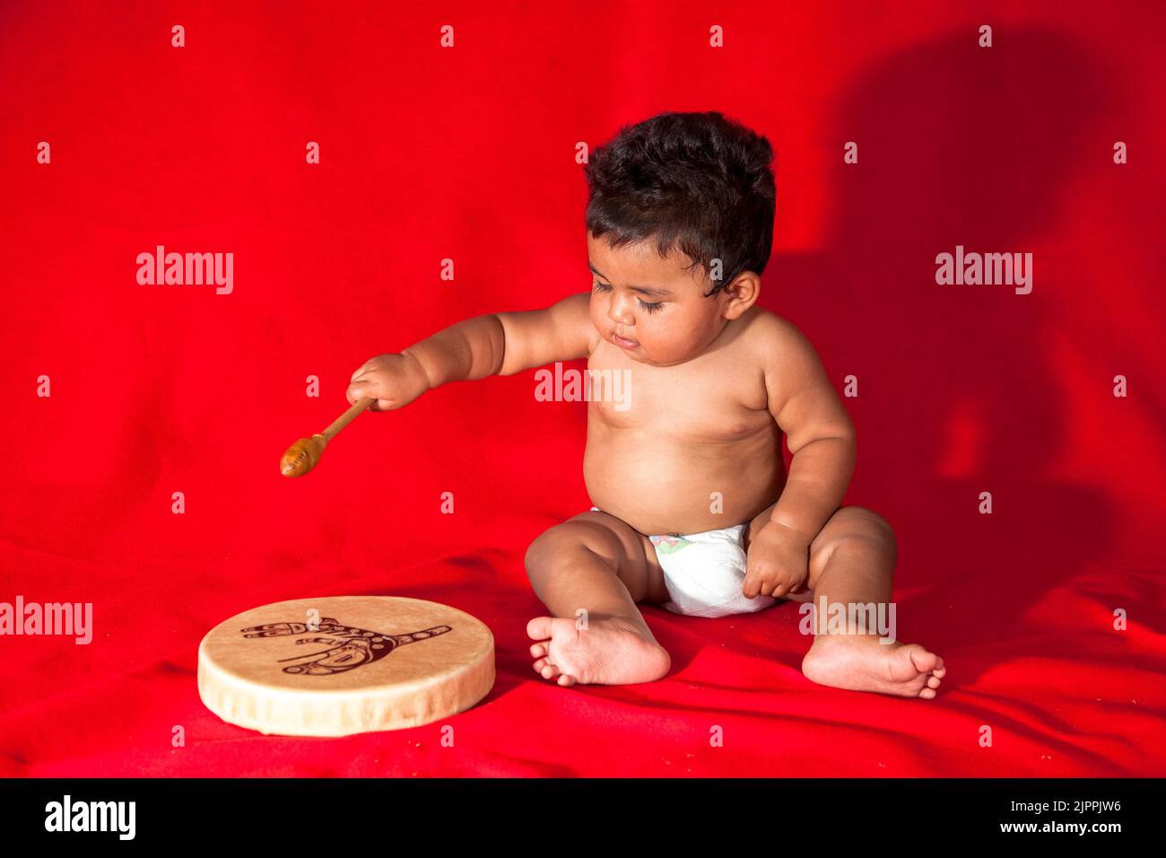 Happy Native American baby plays a traditional hand drum form the ...