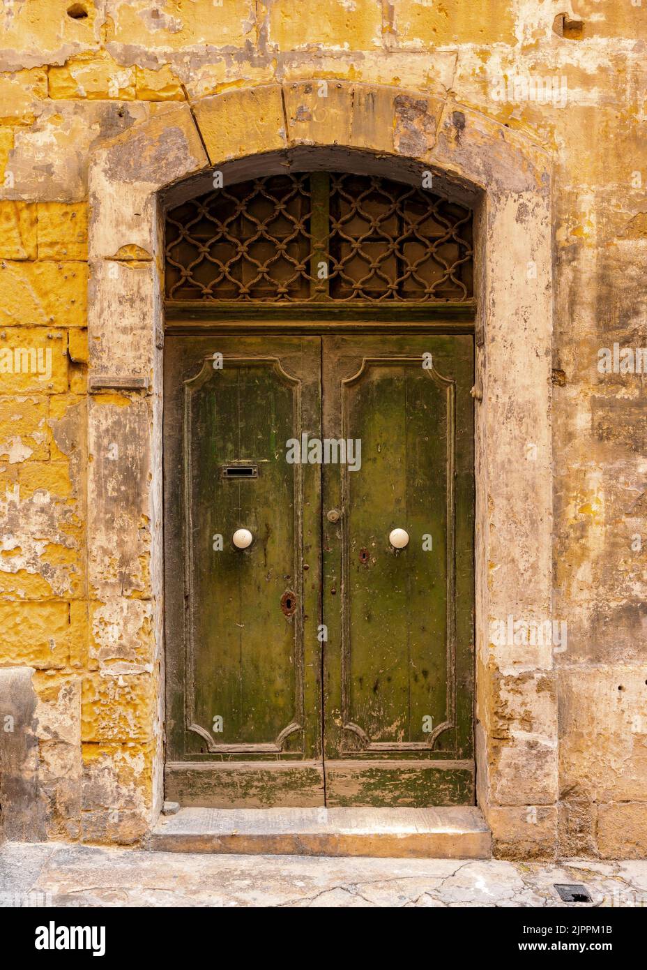 A vertical shot of a vintage green front door of a yellow brick ...