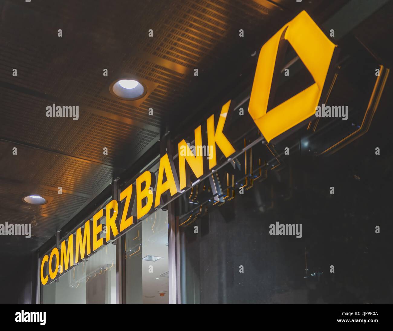 A close up of Commerz bank yellow letters on a bank building at night ...