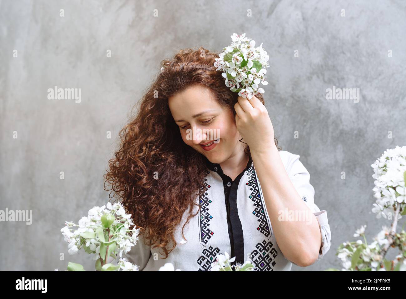 Beautiful curly hair girl in shirt with downcast look. Woman holds ...