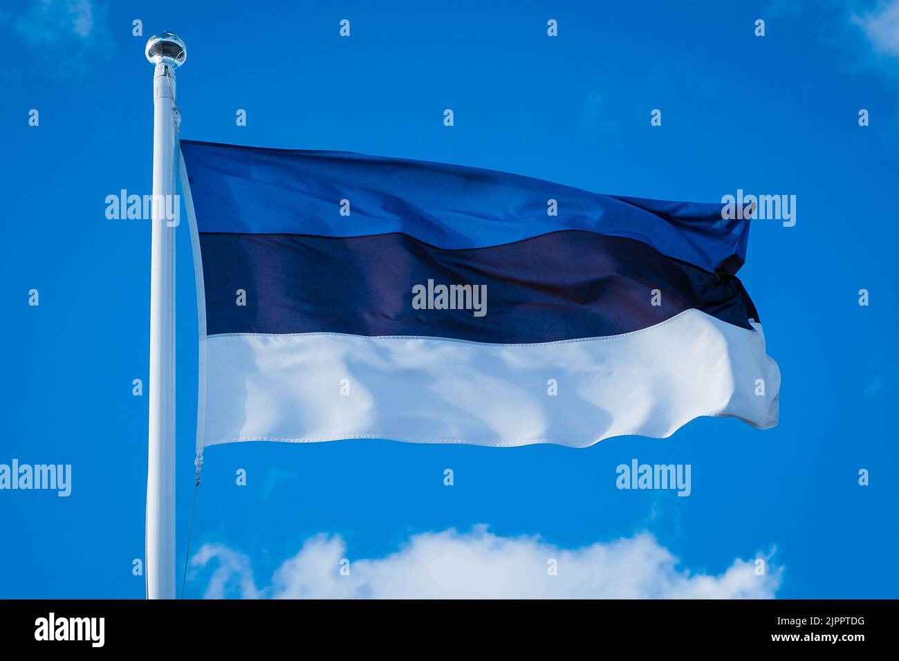 Close-up of flag of Estonia on blue sky background. Estonian flag ...