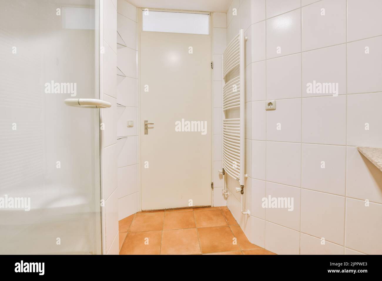 Shower faucets attached to tiled wall near glass partition and ...