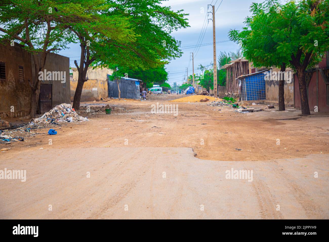 A polluted environment in a poor neighborhood with garbage under trees ...