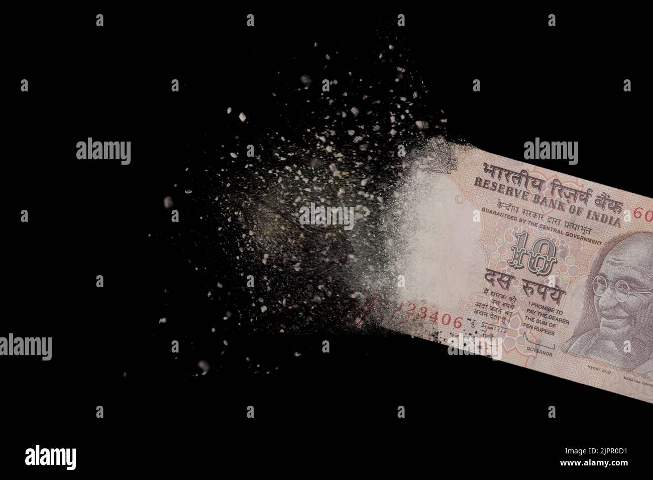 A disintegrating Indian rupee banknote on black background - inflation ...
