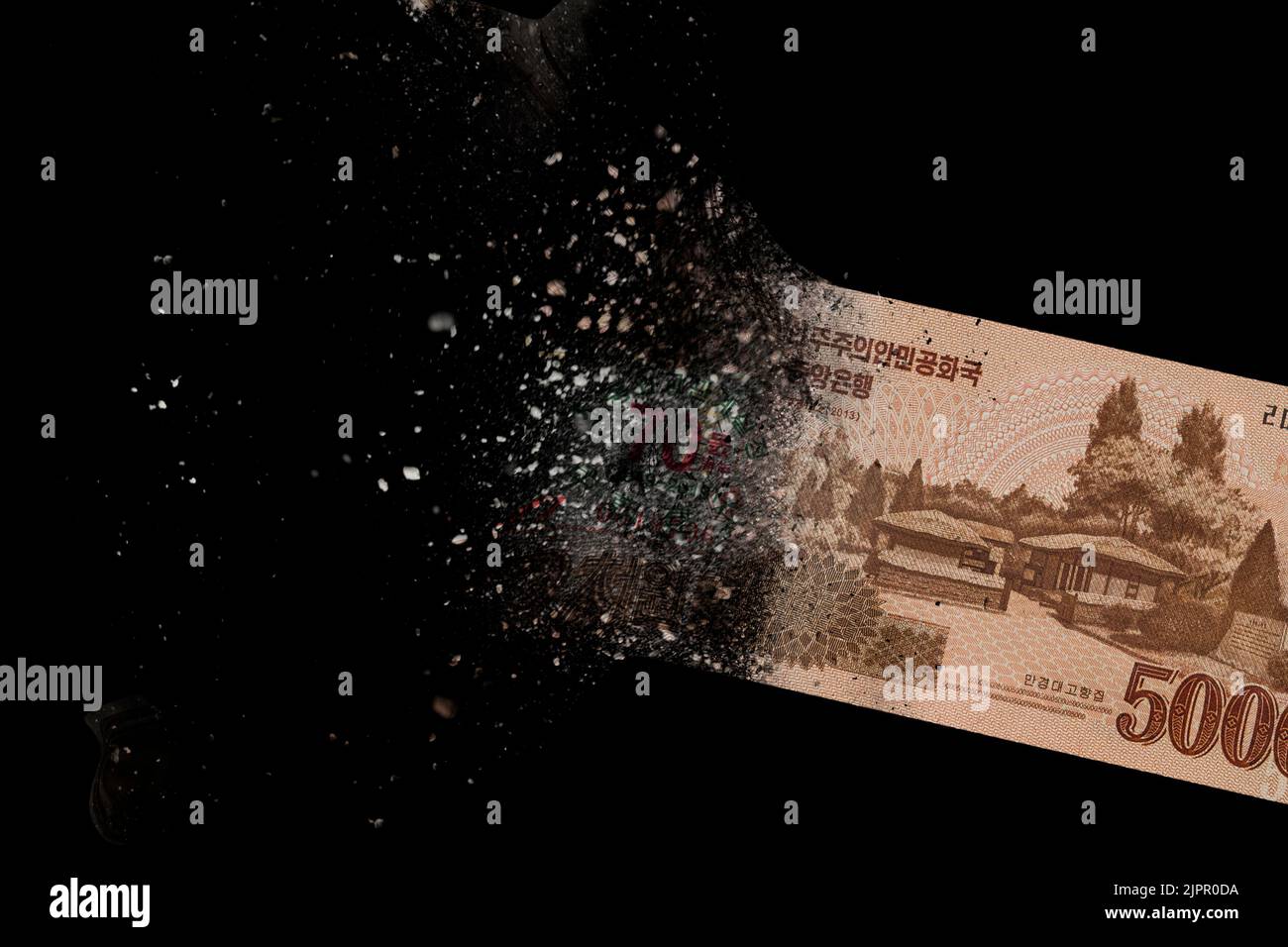 A disintegrating North Korean won banknote on black background ...
