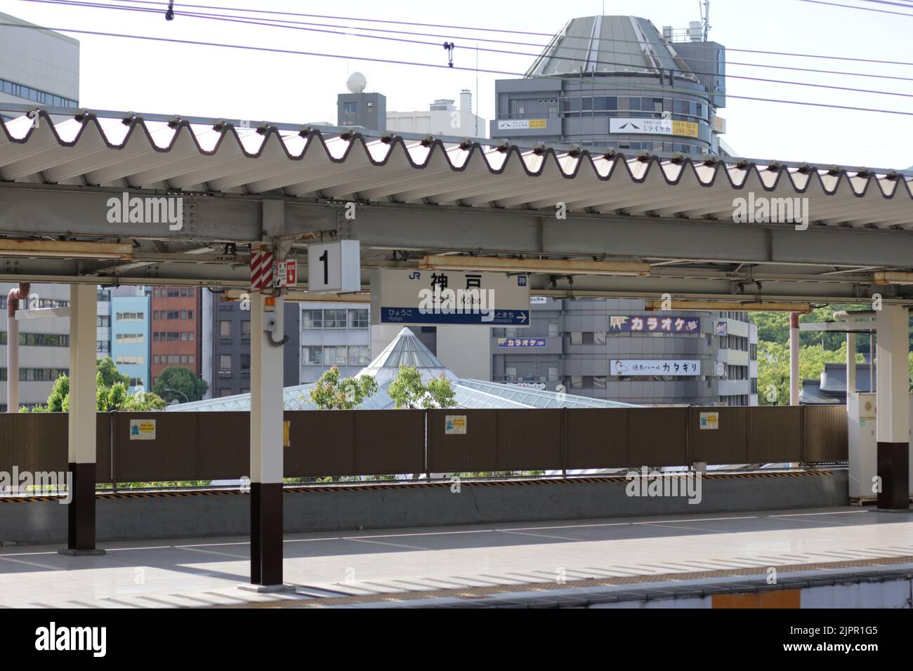 An empty train station with buildings in the background in Kobe, Japan ...