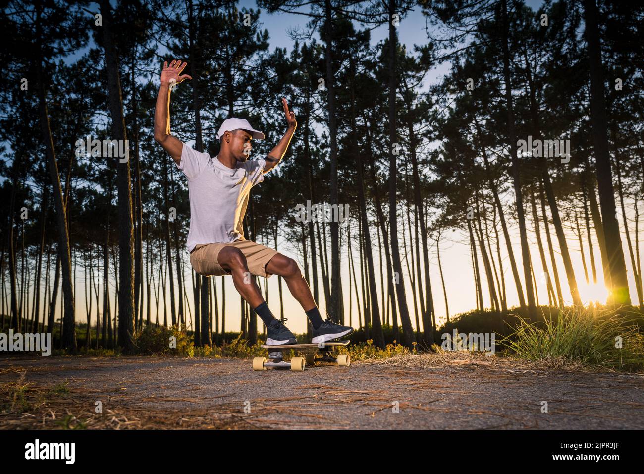Surf skater performing a slide by the pine forest at sunset in Maceda ...