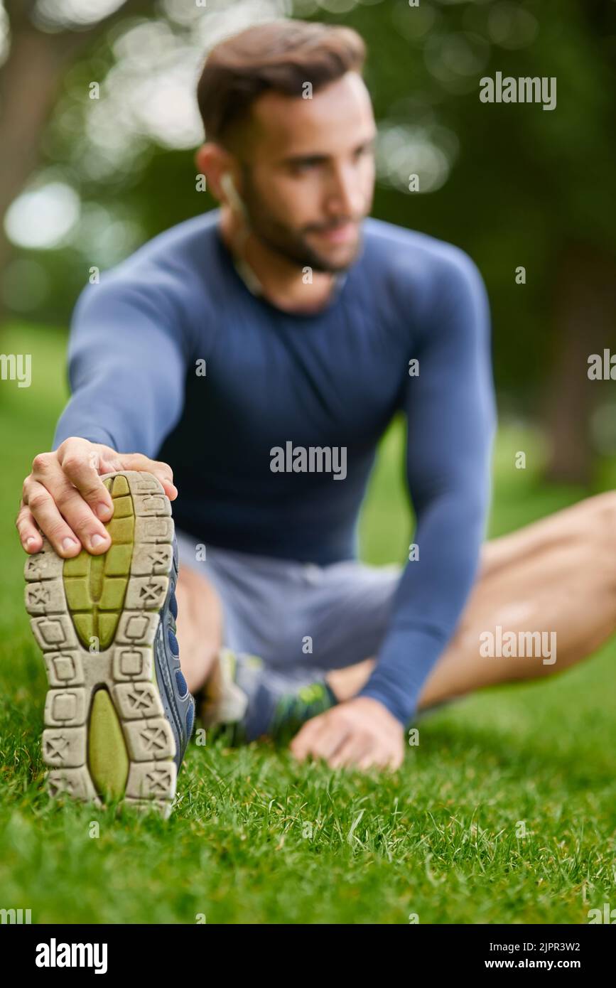 Stretch properly to avoid injury. a handsome young male runner warming ...