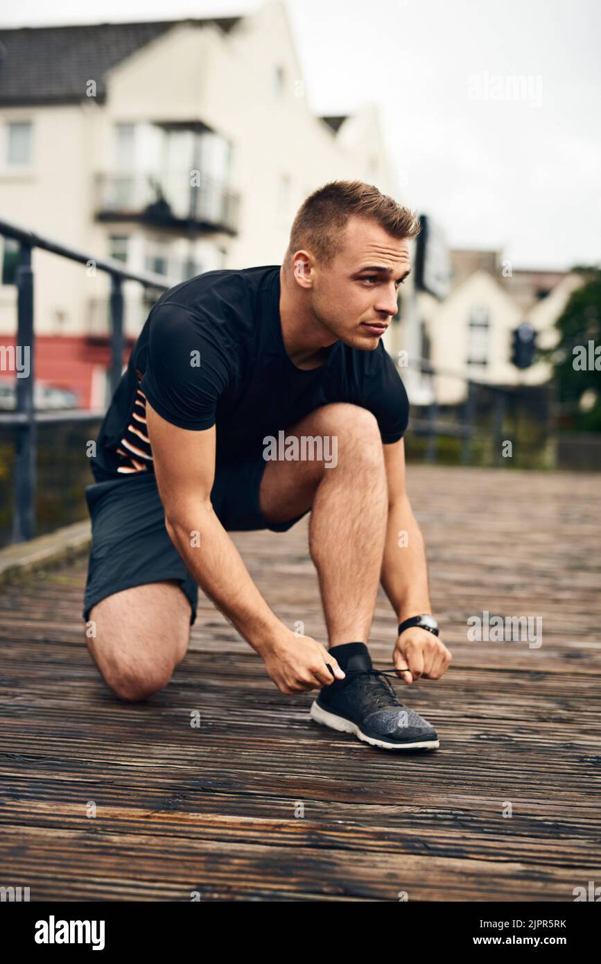 Get your gear in check first. a sporty young man tying his shoelaces ...