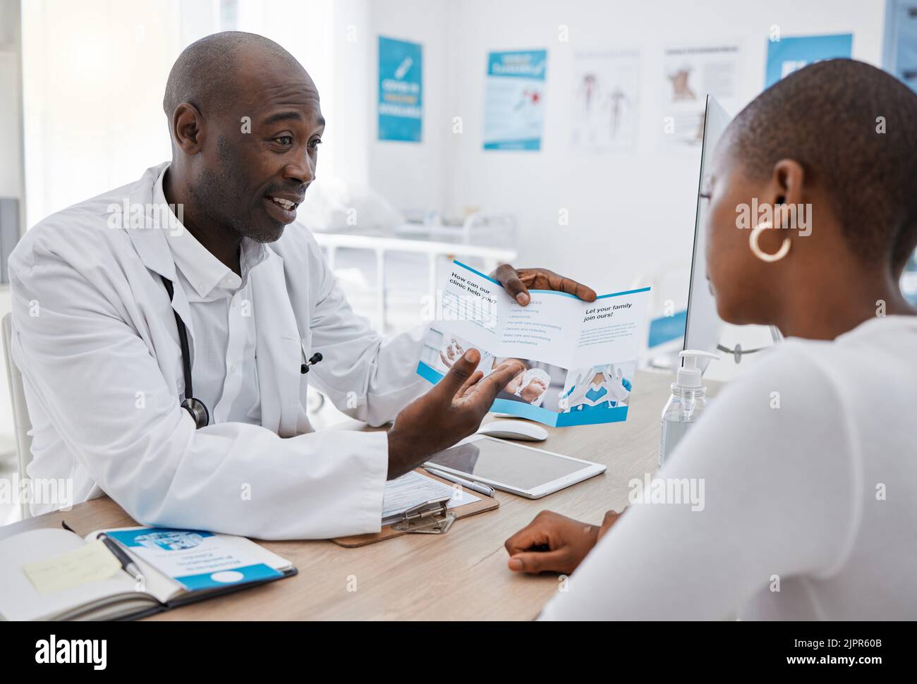 A doctor giving patient hospital information at a clinic and explaining ...