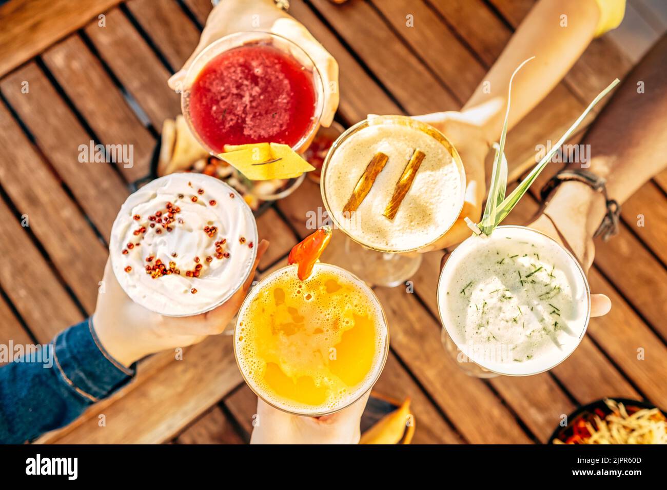 Friends toasting, saying cheers holding tropical fruit cocktails ...