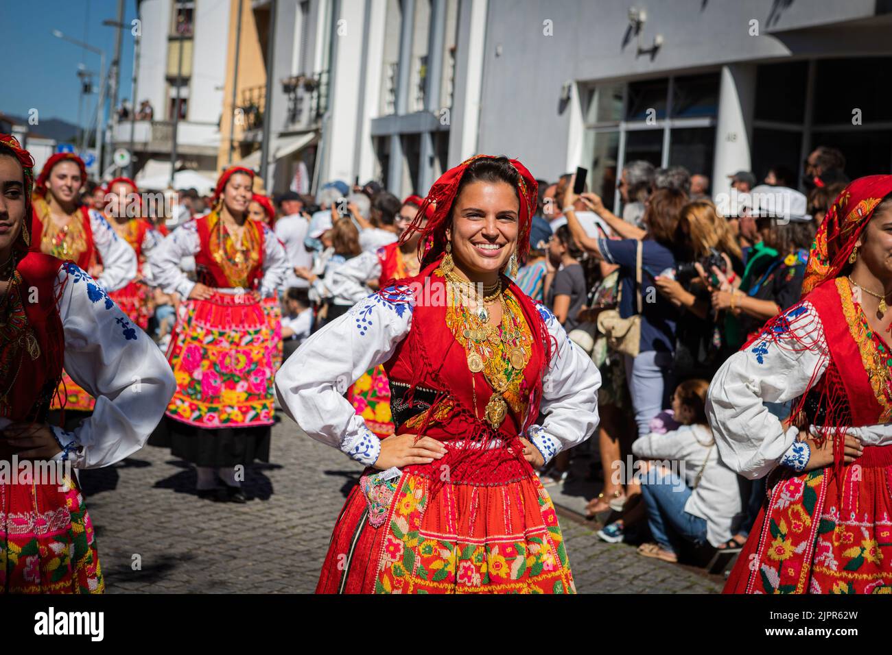 Women are seen walking the parade in traditional red costumes. More ...