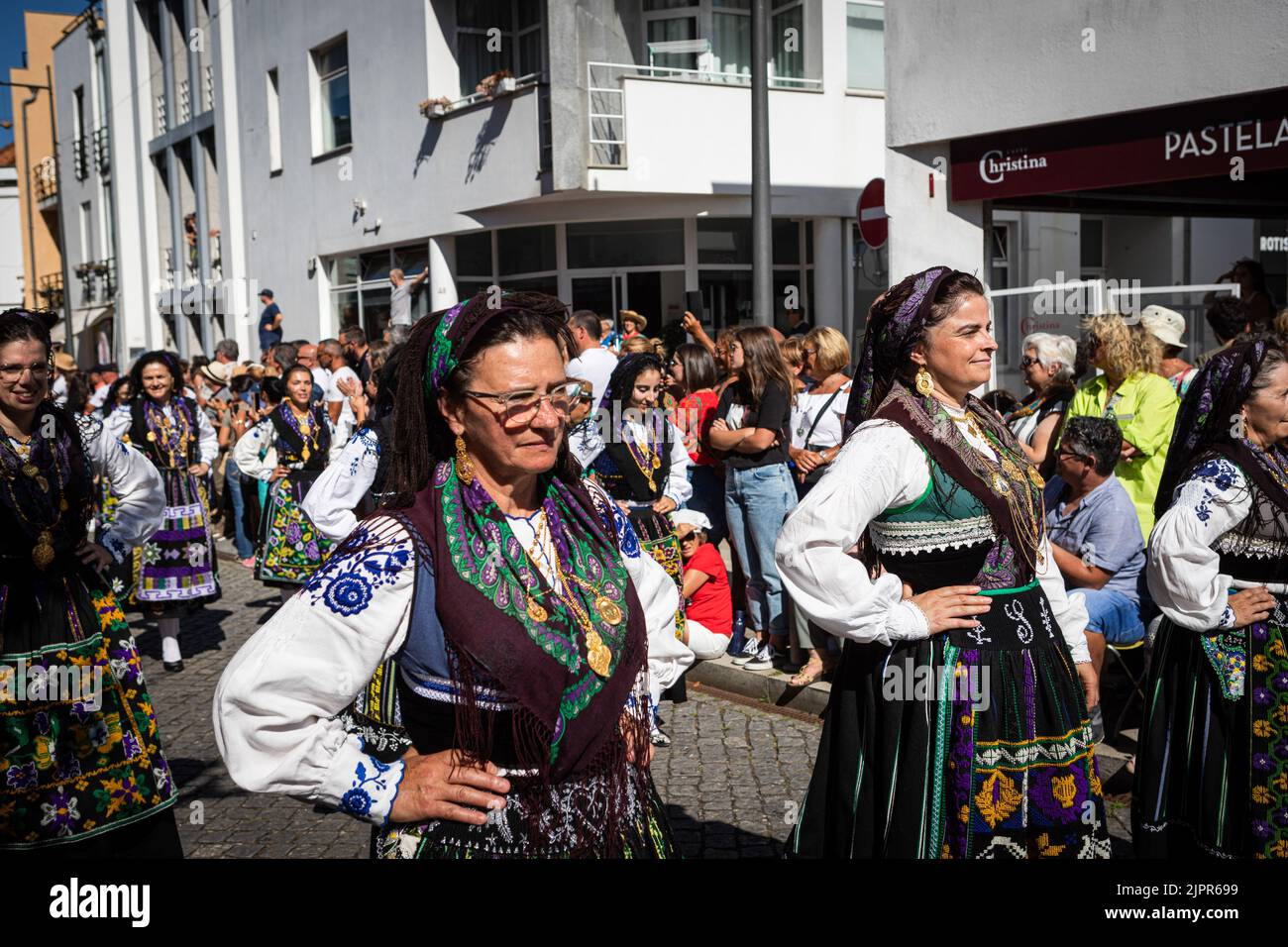 Women wearing traditional costumes in black, green, and purple walk the ...