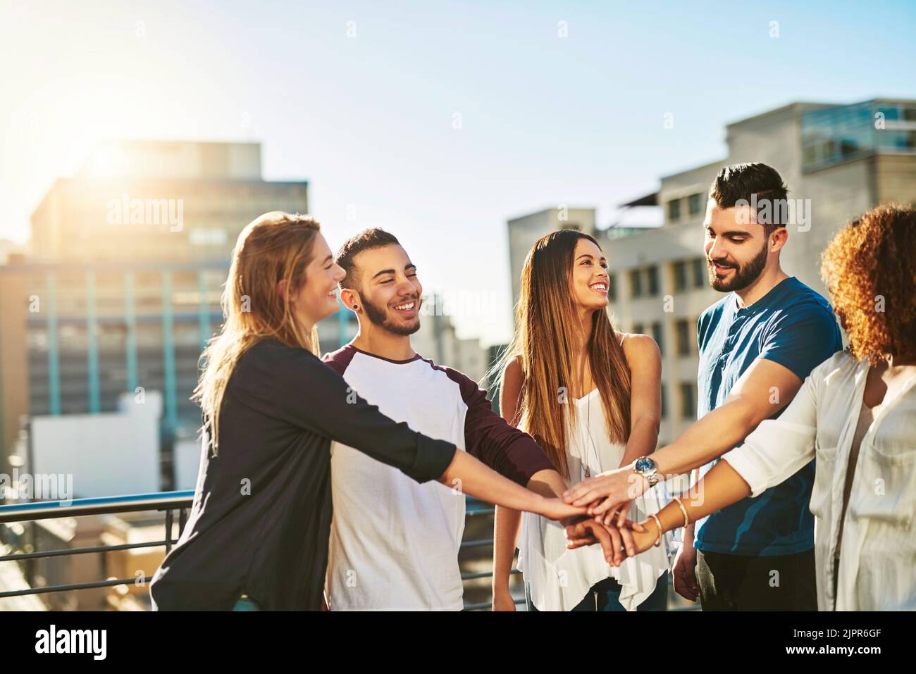 Group support. a group of young people putting their hands together in ...