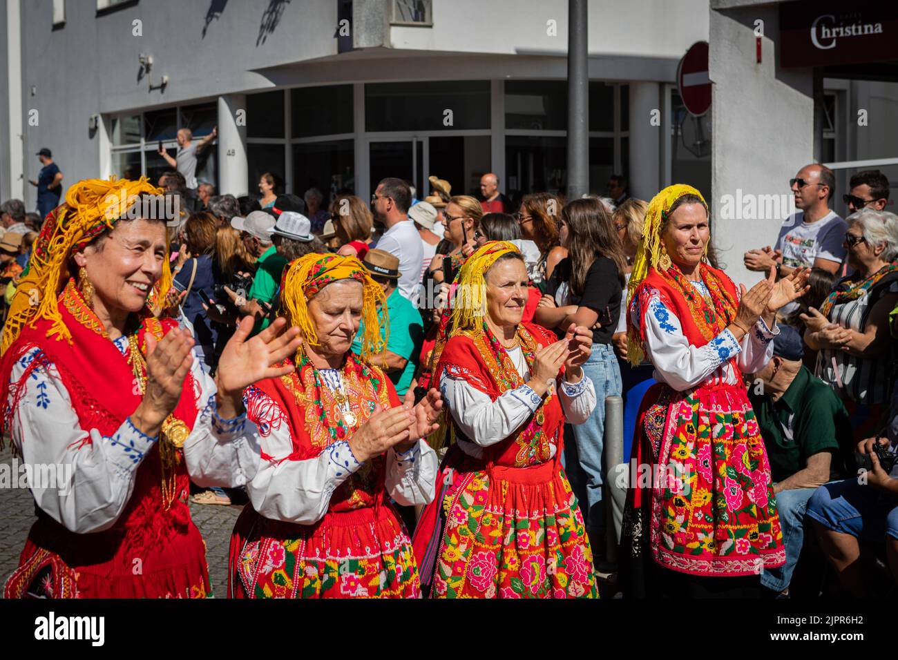 A group of women wearing traditional red costume seen clapping their ...