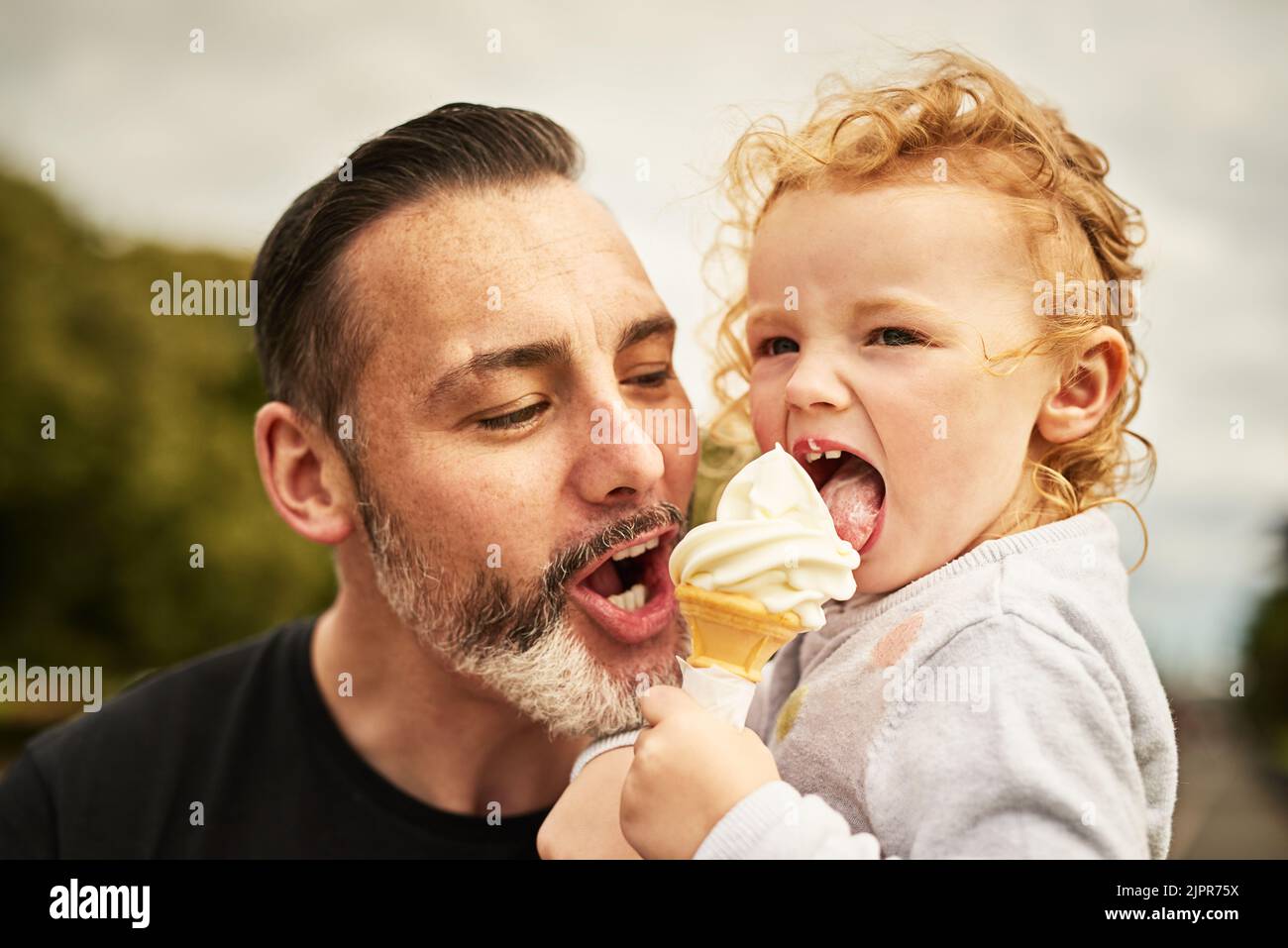 Ice cream is instant happiness. a father and his little daughter eating ...