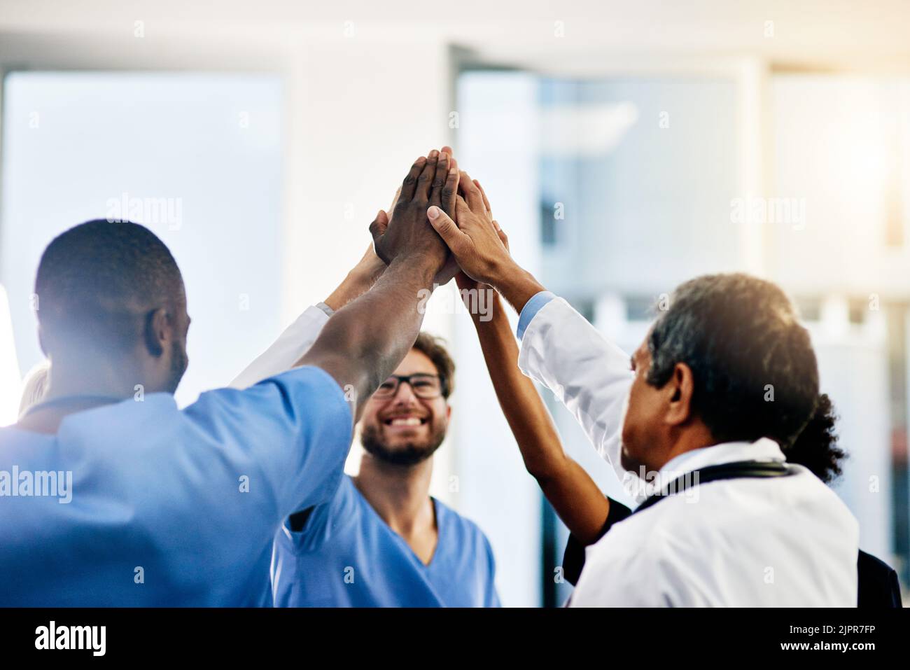 Celebrate every medical success. a diverse team of doctors giving each other a high five in a ...