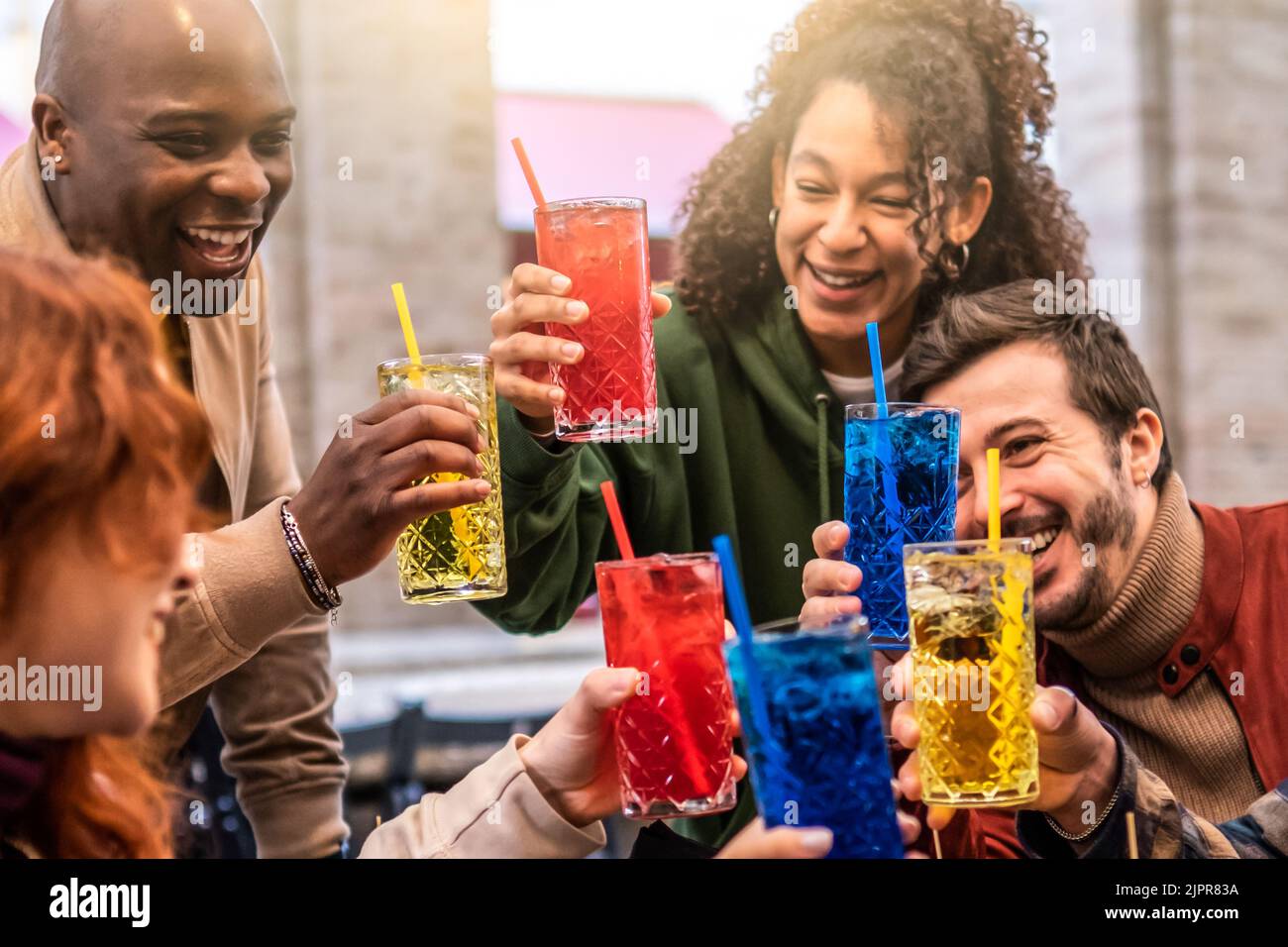 Happy multiracial friends group laug drink and eating at restaurant ...