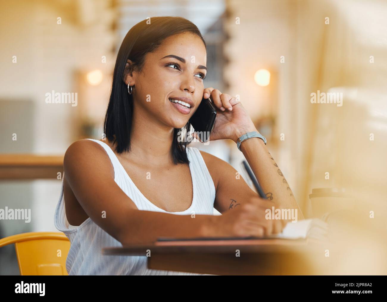 Freelance worker working in a coffee shop talking on a phone call about ...