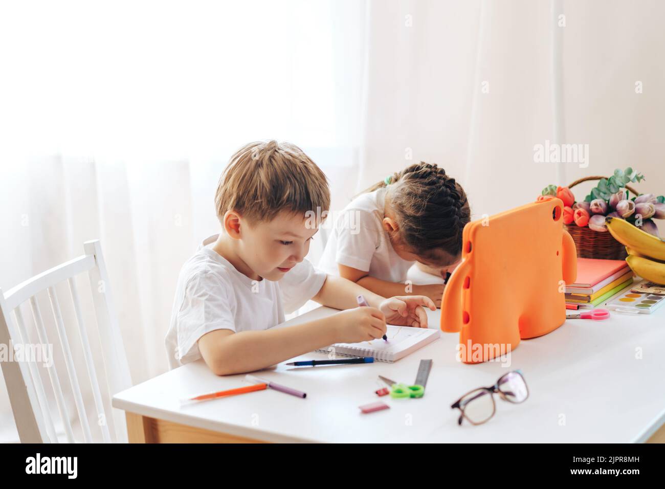 Children draw in a notebook and watch a lesson on a tablet Stock Photo ...