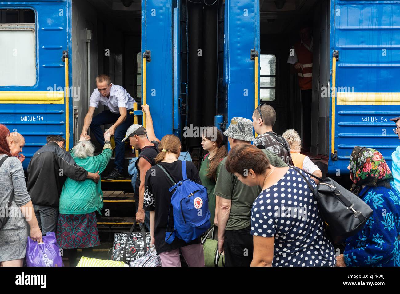 A male railroad worker helps an elderly woman board an evacuation train ...