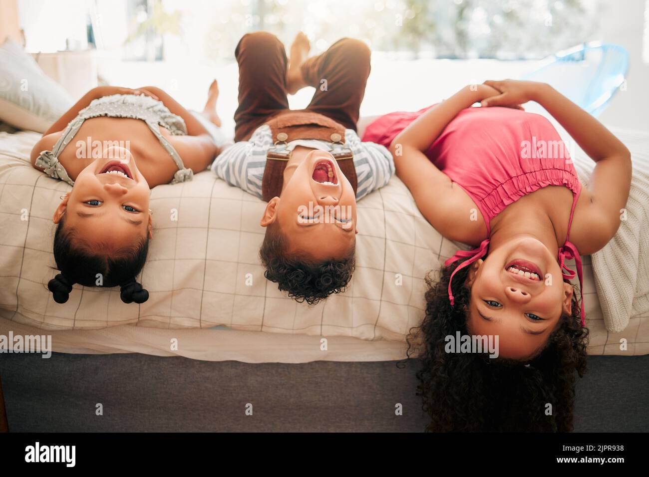 Silly kids playing upside down on bed enjoy and having fun together in ...