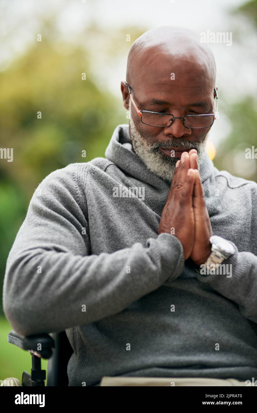 Drawing strength from above. a senior man praying while sitting in her ...