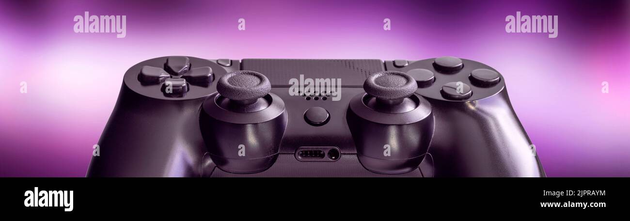 black video game controller isolated on a blurred lilac background ...