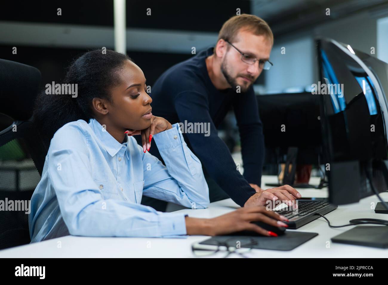 Colleagues look at the monitor and decide working moments. Caucasian man helps sad african woman ...