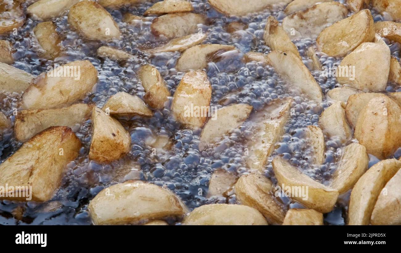 French fries are fried in a pot, with boiling oil many bubbles pops up ...