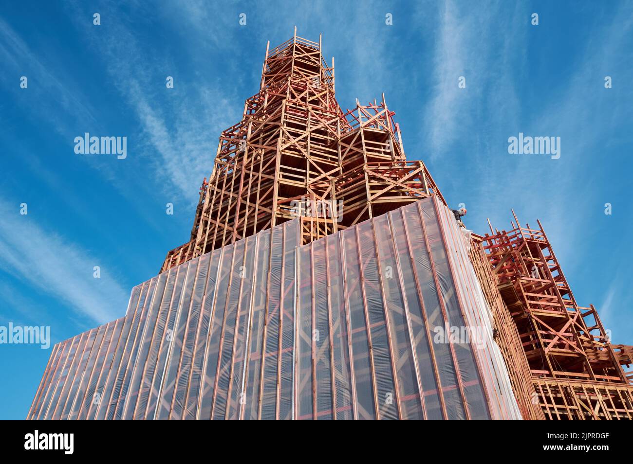 Scaffolding from wooden beams and film, around the building against a ...