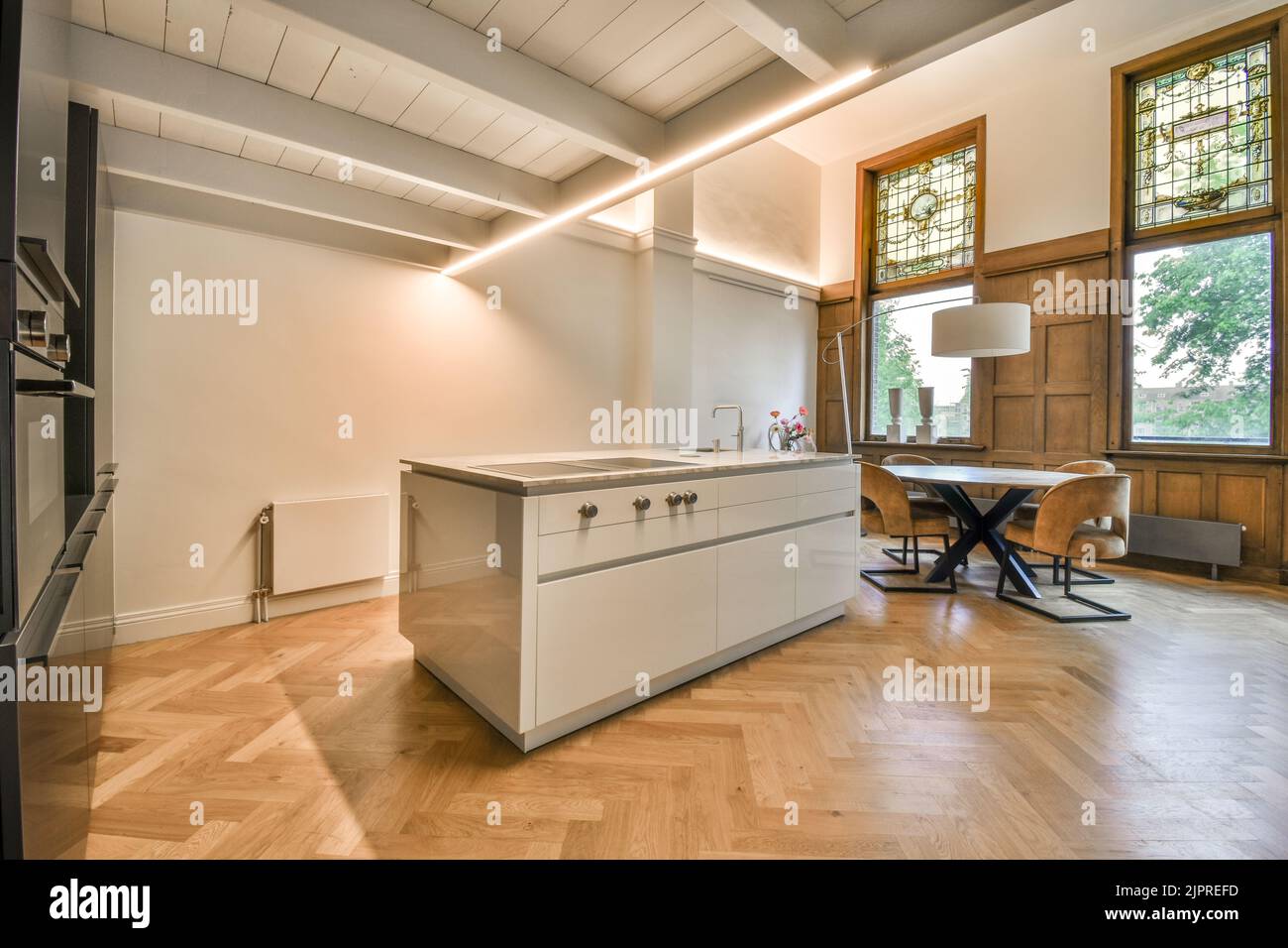 Wooden table and comfortable chairs placed near kitchen furniture in ...