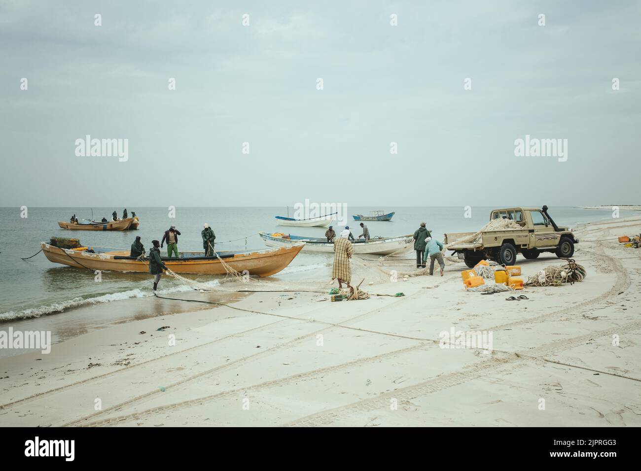 Loading a net onto a fishing boat on the beach, fishing village on the ...