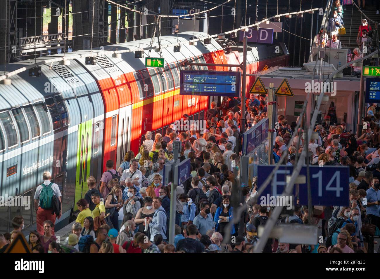 Many people standing crowded on a platform in front of a local train ...