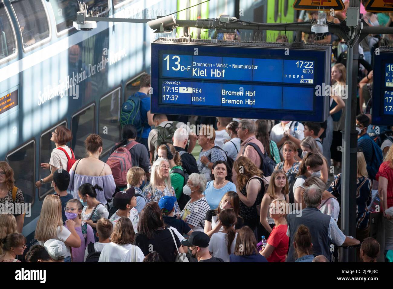 Many people standing crowded on a platform in front of a local train ...