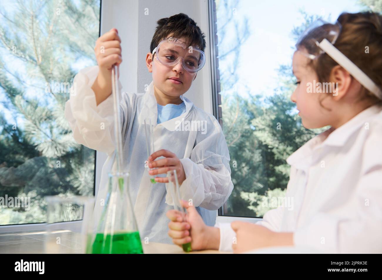 Kids doing chemical experiment, analyzing and mixing liquid in flasks ...