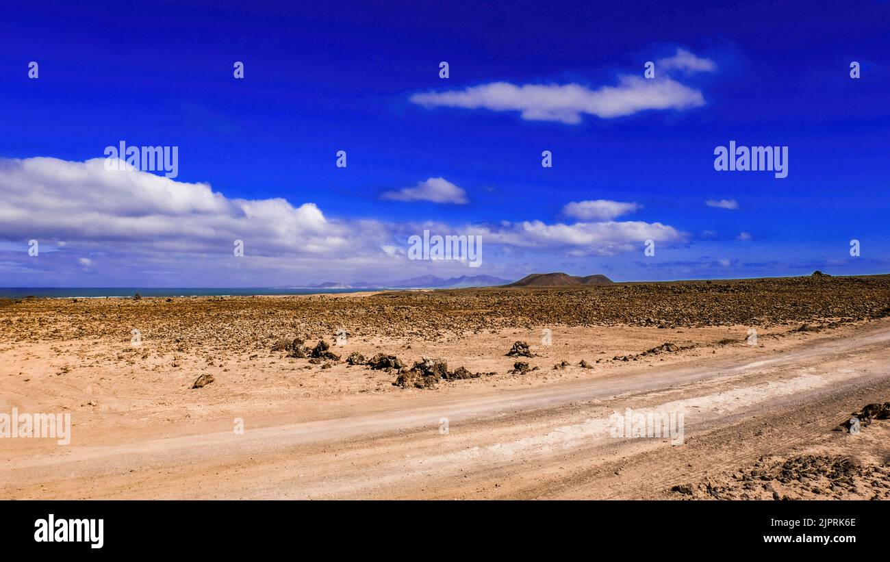 A scenic view of a road in plains under a cloudy blue sky Stock Photo ...