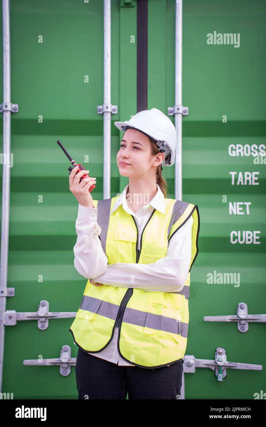 Female Foreman stay in front of container cargo using walkie talkie for ...