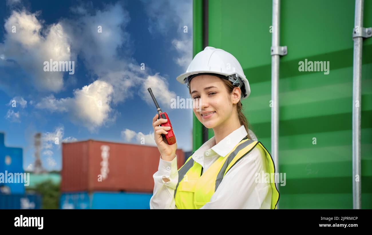 Female Foreman stay in front of container cargo using walkie talkie for ...
