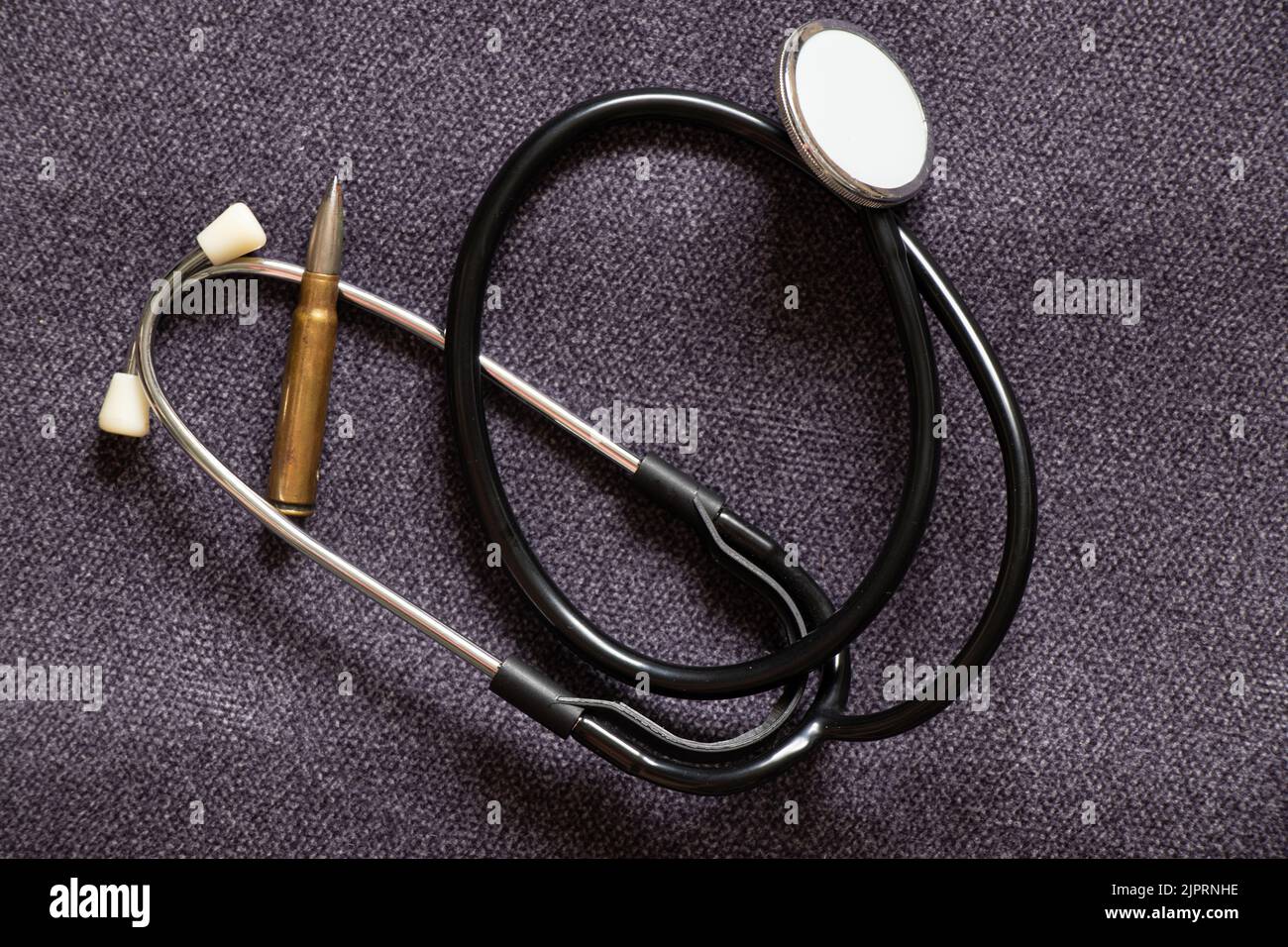 Stethoscope of a doctor and a bullet of a soldier ledat on a gray ...