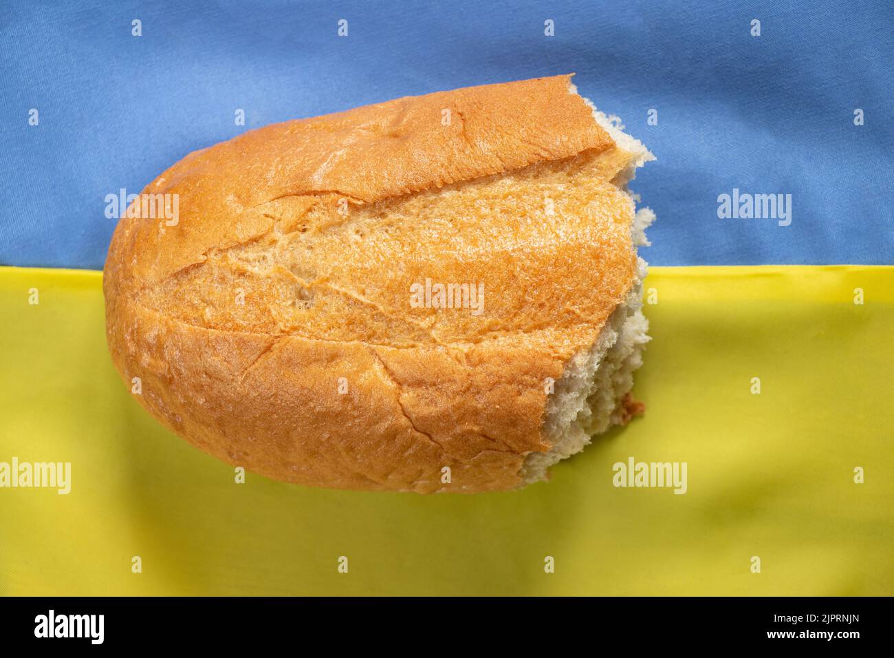 A loaf of broken bread against the background of the national flag of ...