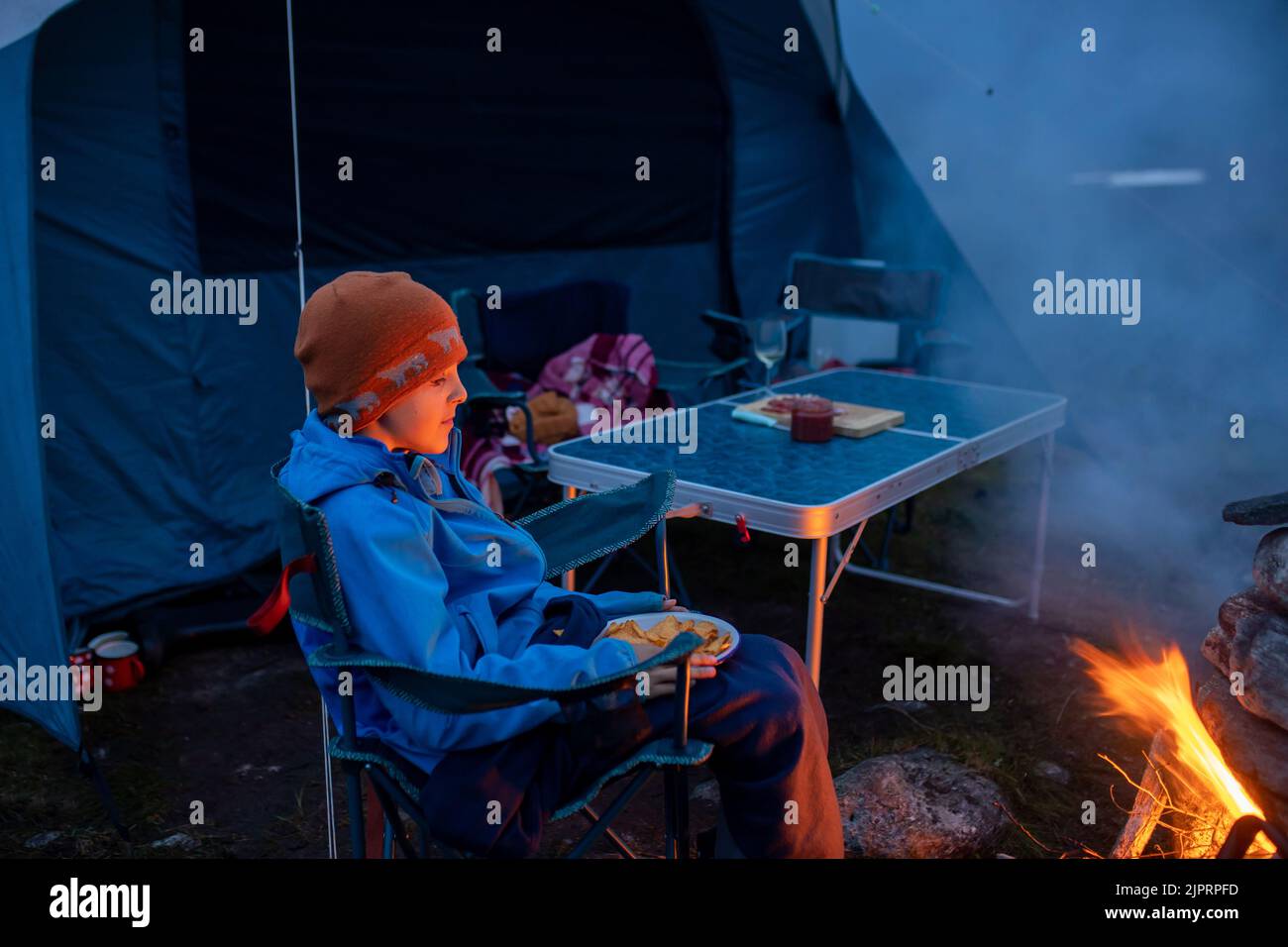 Kids, sitting around campfire at night, enjoying wild camping, family ...
