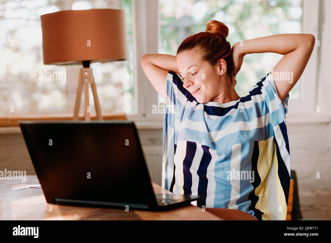 A tired female sitting at home desk falling asleep working too long at ...