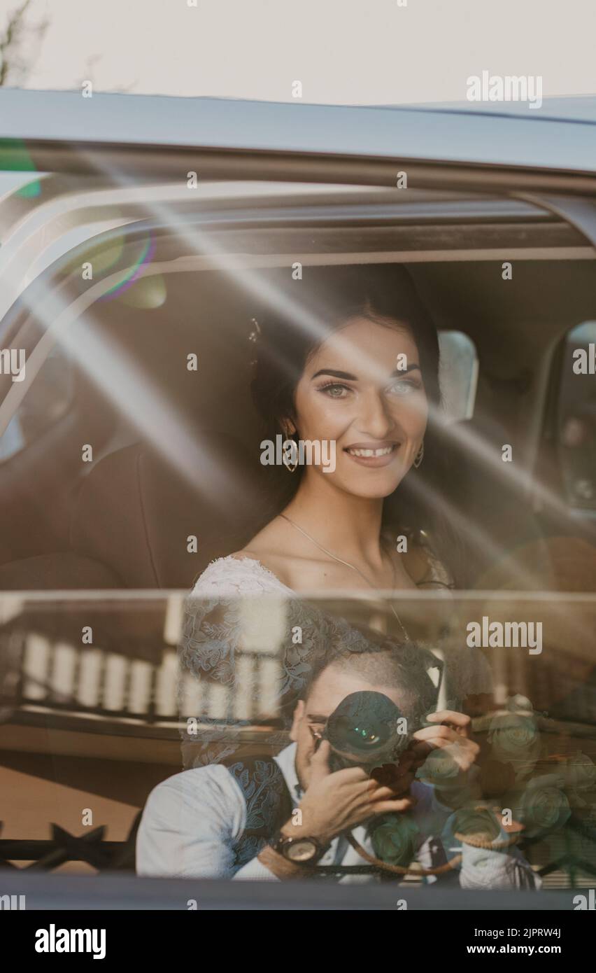 A vertical shot of the bride in the car and the photographer's ...