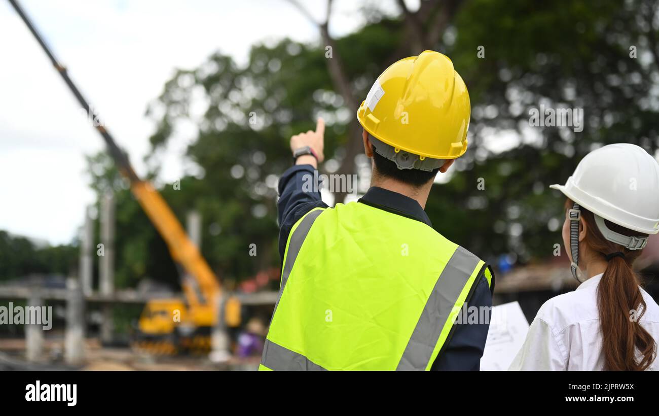 Rear view of civil engineers and specialists checking plan at ...