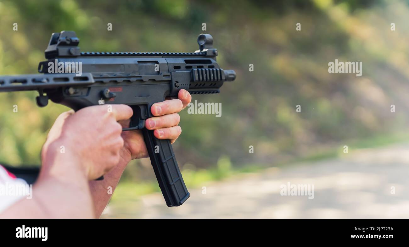 Hands holding submachine gun during training on shooting range. Blurred ...