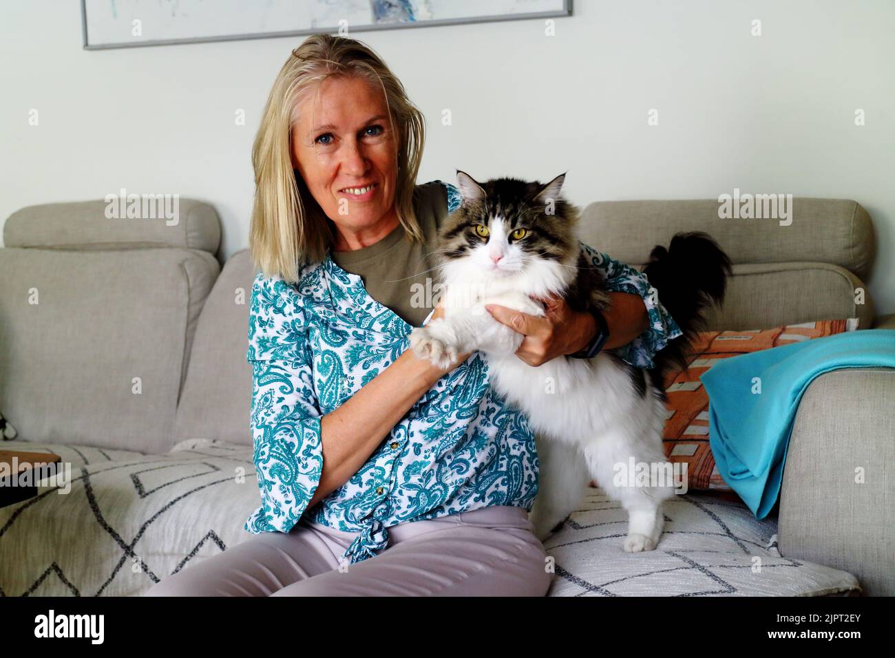 Middle aged smiling blonde woman sitting on a couch with a scruffy ...